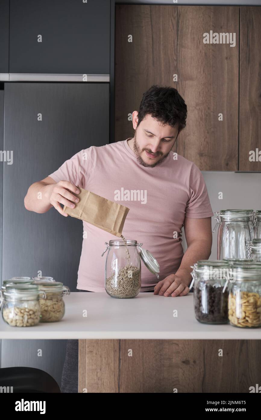 Young latin man filling up a jar with peeled sunflower seeds from a ...