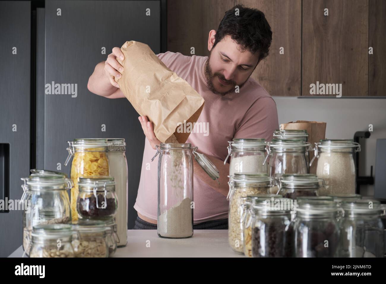 Young latin man filling up a jar with whole wheat flour from a paper ...