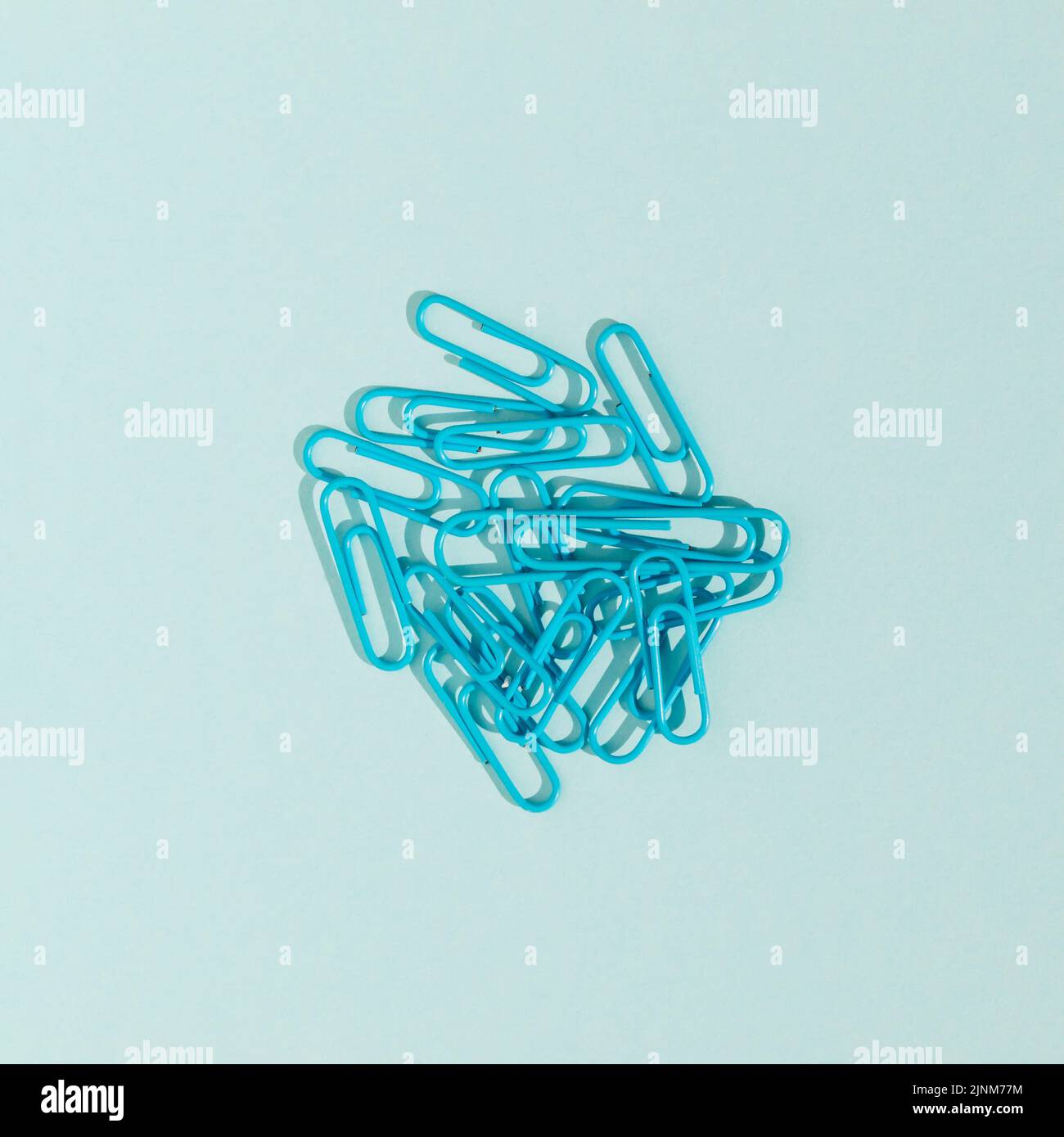 Paper clips isolated on blue background. Monochromatic composition ...