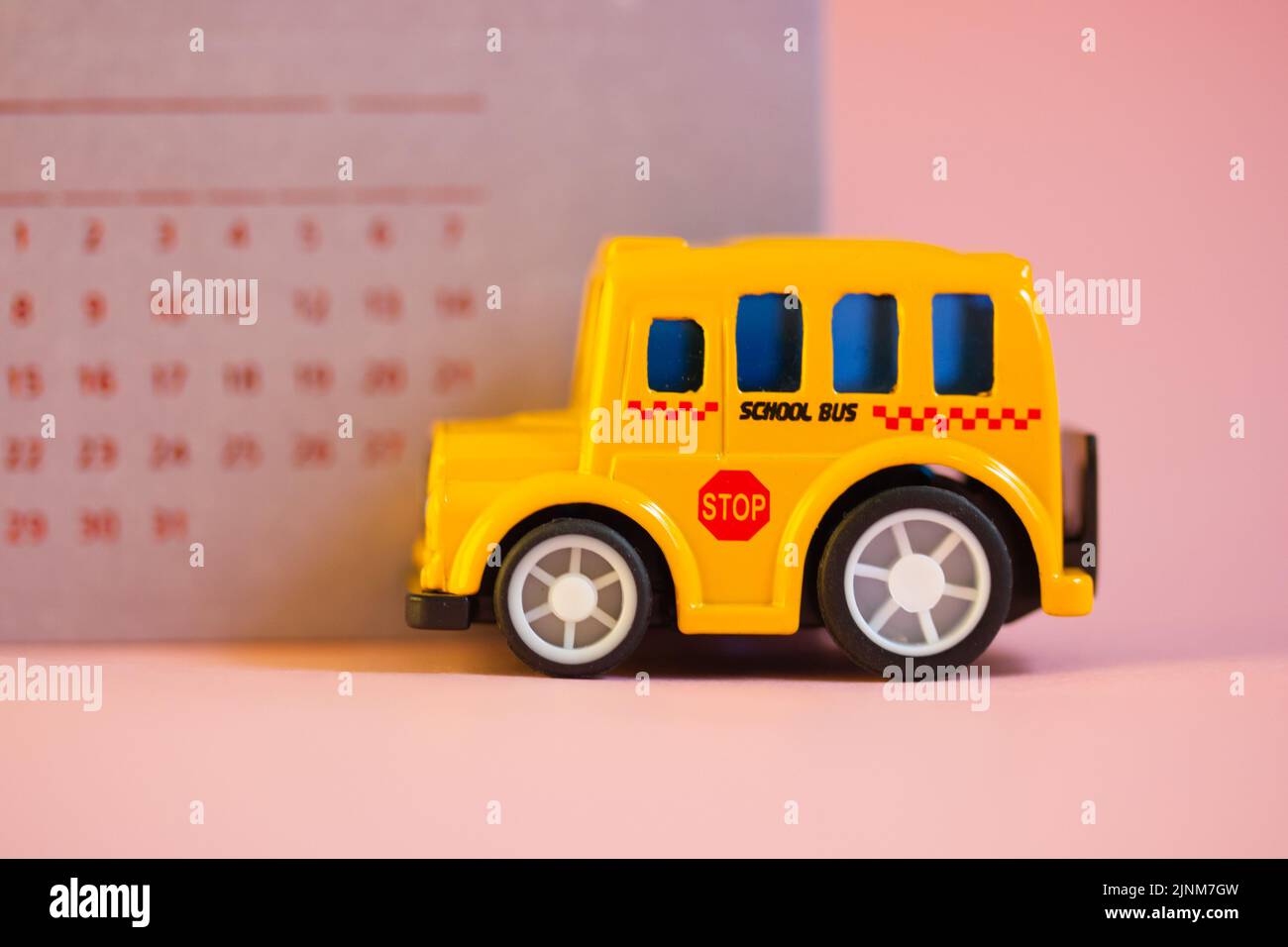 Toy yellow American school bus on violet calendar with dates background ...