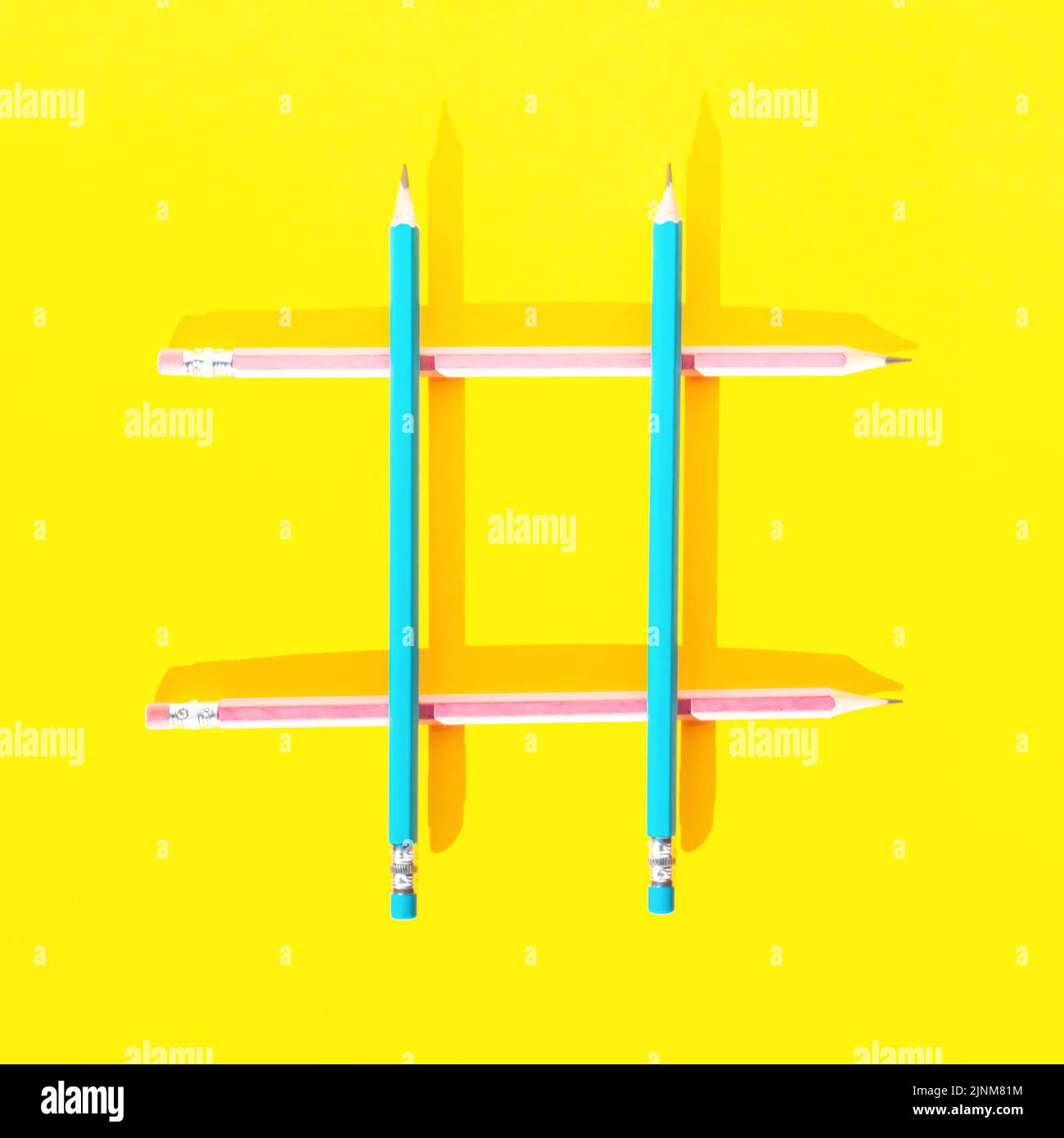 Four wooden pencils on yellow background assembled in a shape of ...