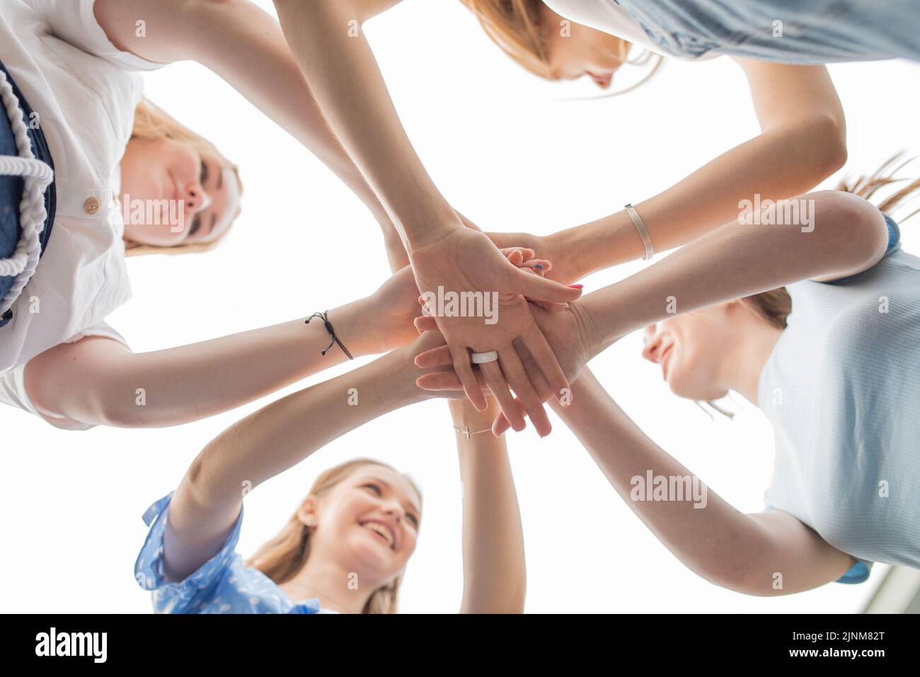 Bottom view of young wonderful women folding stacking joining hands on ...