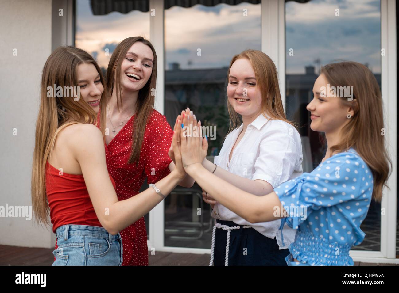 Group of young happy gorgeous women folding hands in stack, giving high ...