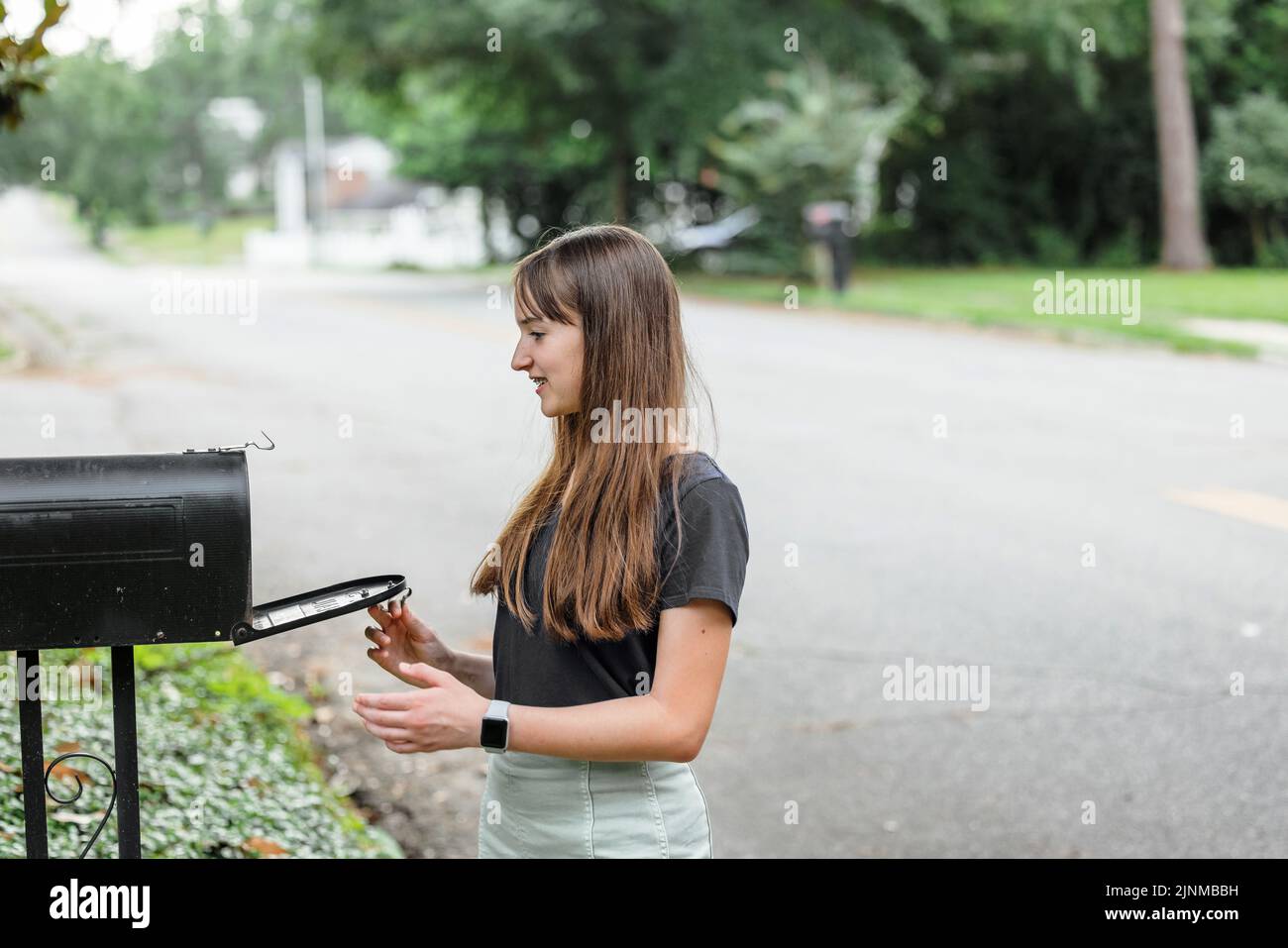 A teen brunette girl with long hair checking the mailbox for letters ...