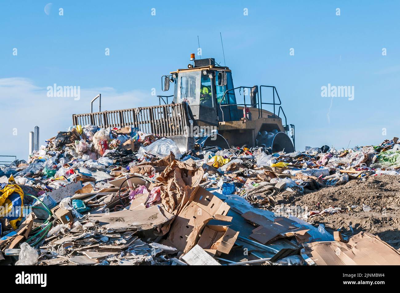 A heavy equipment soil compactor / bulldozer pushes refuse around at an ...