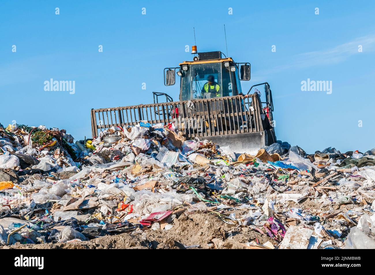 A heavy equipment soil compactor / bulldozer pushes refuse around at an ...