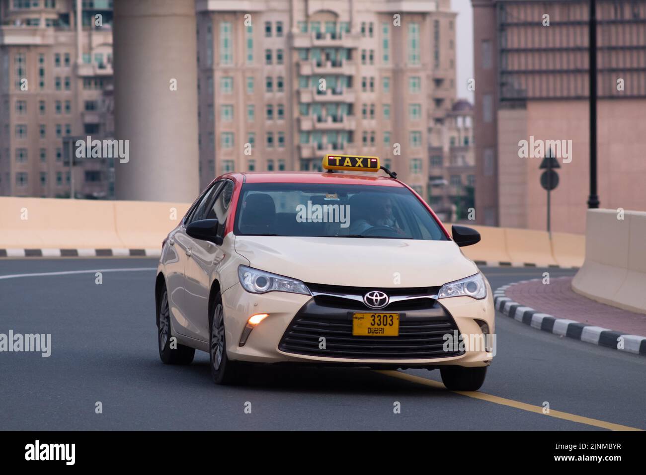 Close-up of Dubai Taxi as it passes a curve on the road in the urban ...