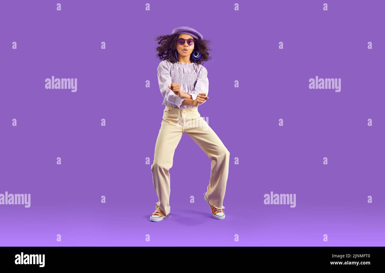Child in stylish casual outfit dancing gangnam style on purple studio ...