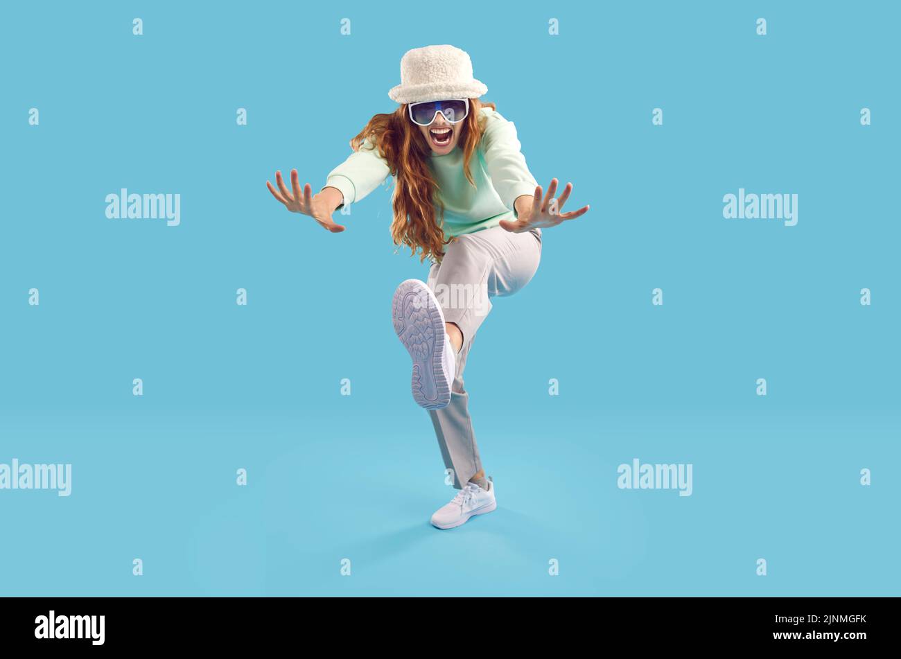 Cheerful crazy and strange young woman having fun on light blue ...