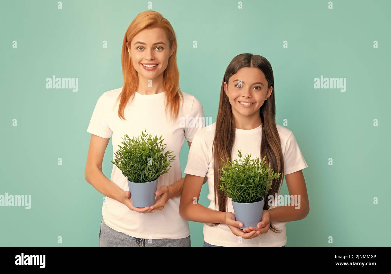 Happy woman mother and adopted daugher child smile holding pot plants ...