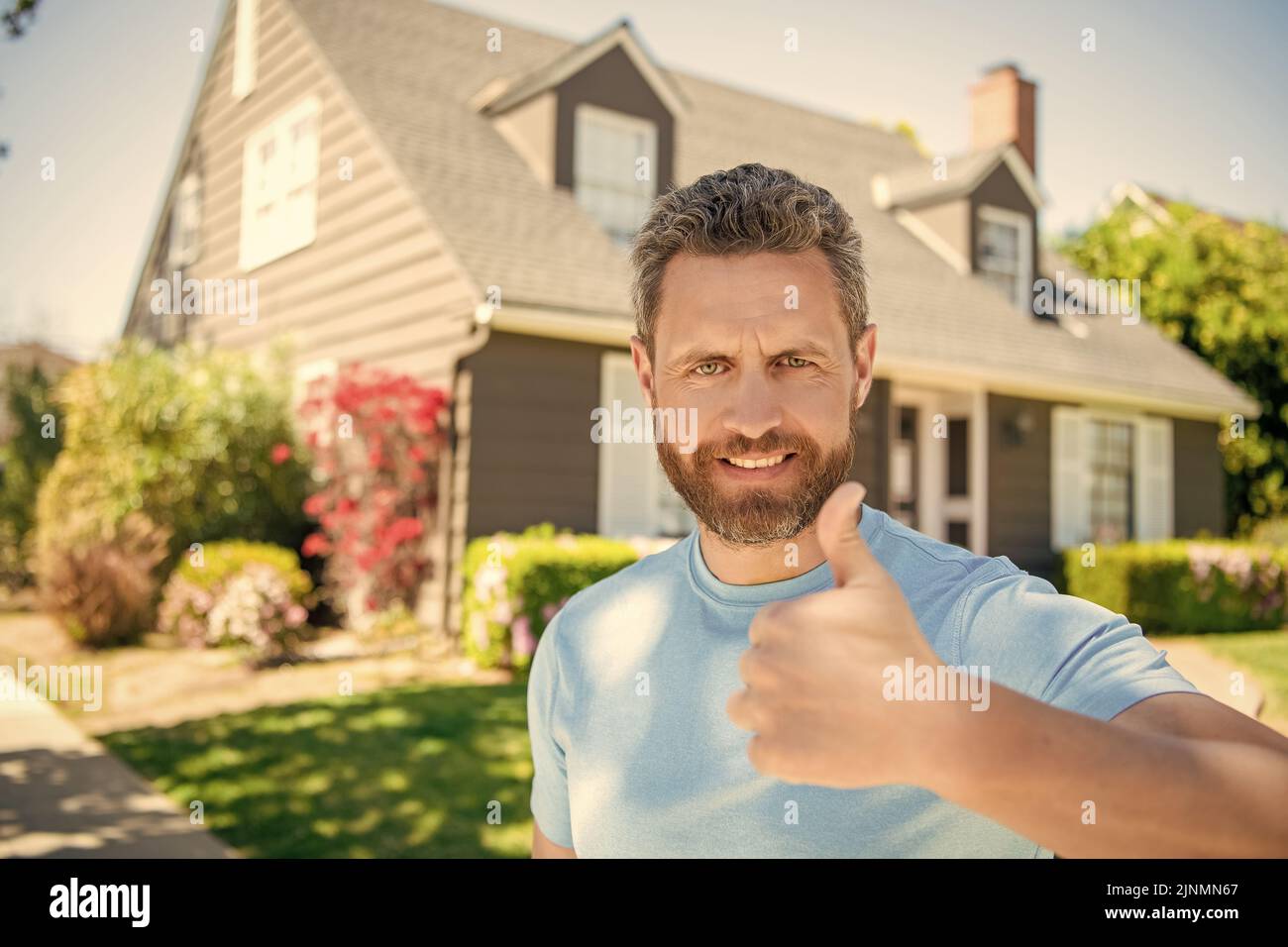 happy bearded man showing thumb up on house background, suburb Stock ...