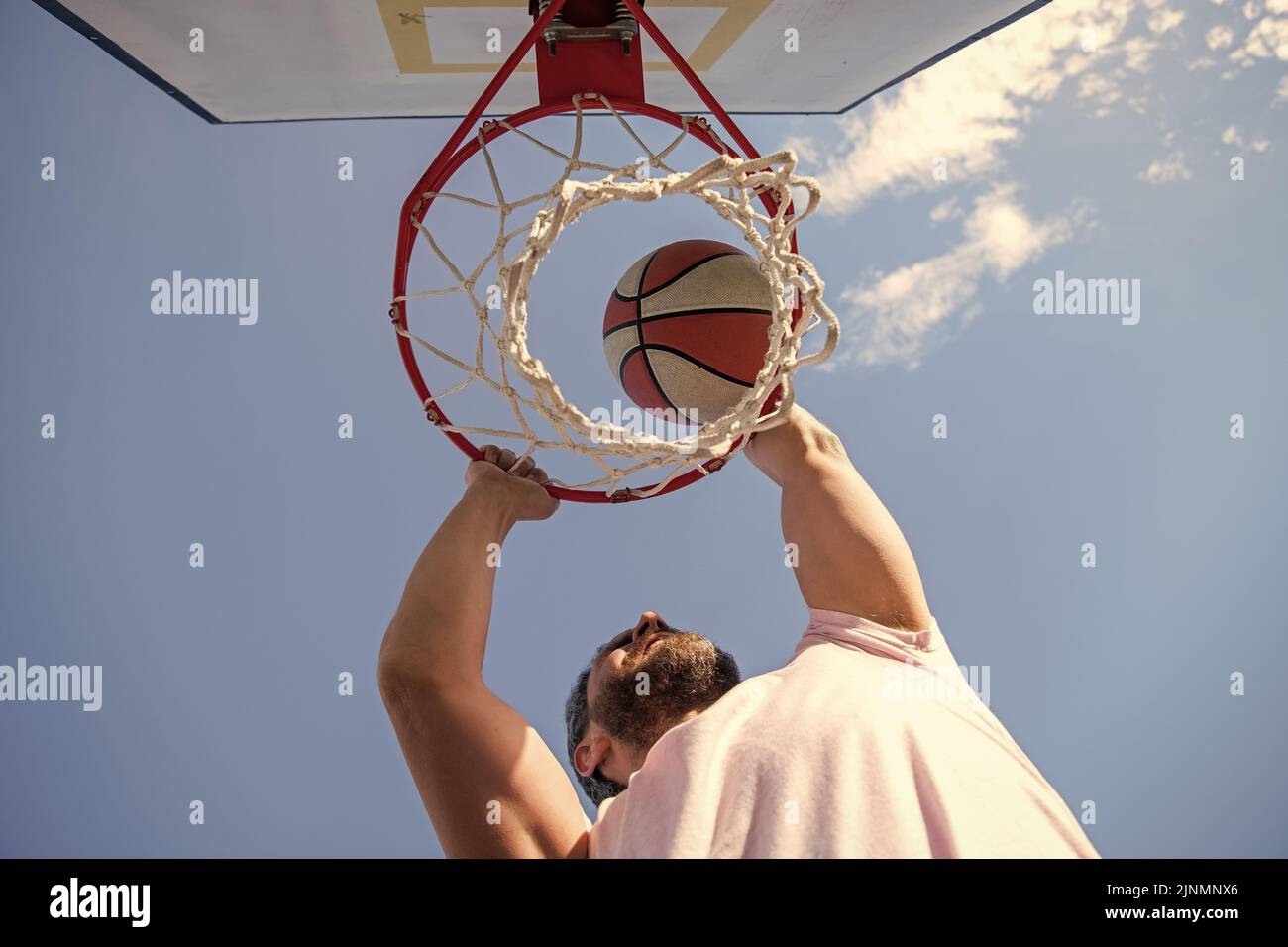 guy dunking basketball ball through net ring with hands, winning Stock ...