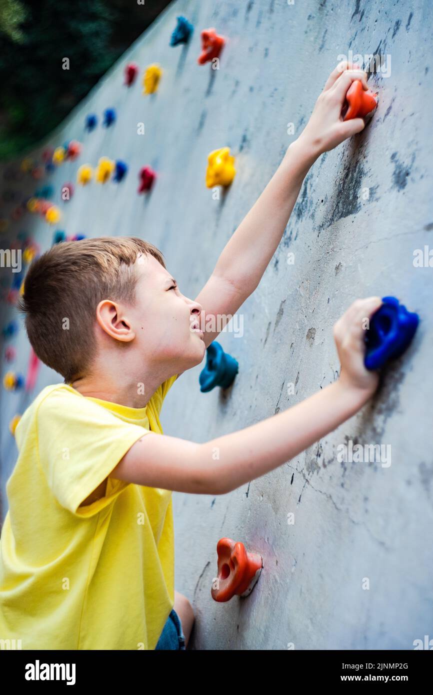Boy playing on climbing wall in summer park zone Stock Photo - Alamy