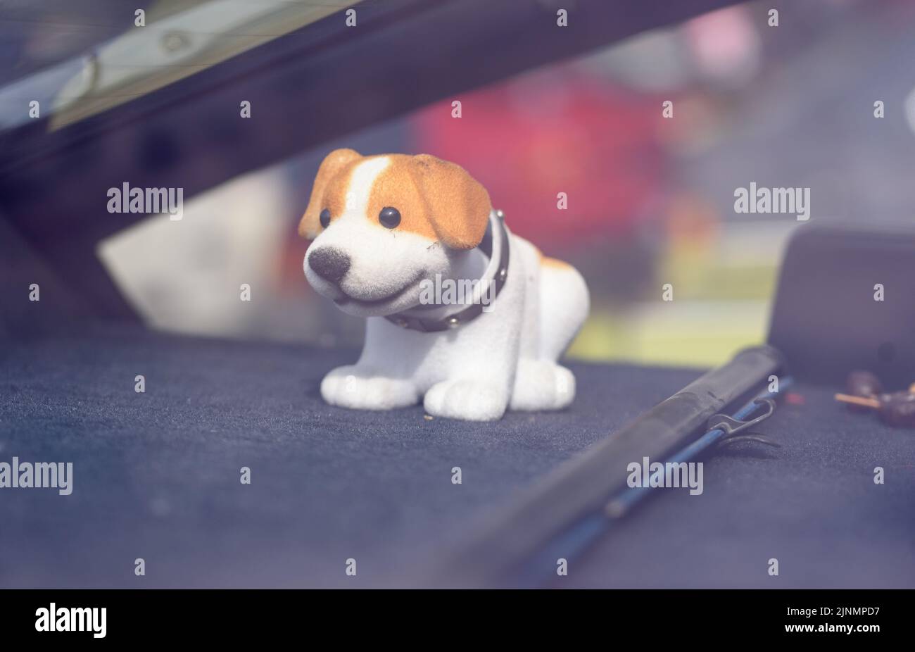 A nodding toy dog on the dashboard of a car on a window background ...