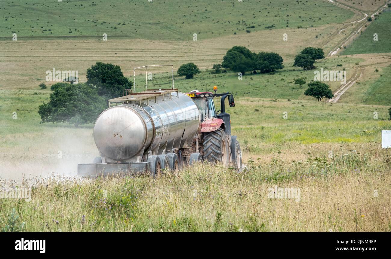 Red Case Puma 340 tractor towing a 30,000 litre water trailer on a dirt ...