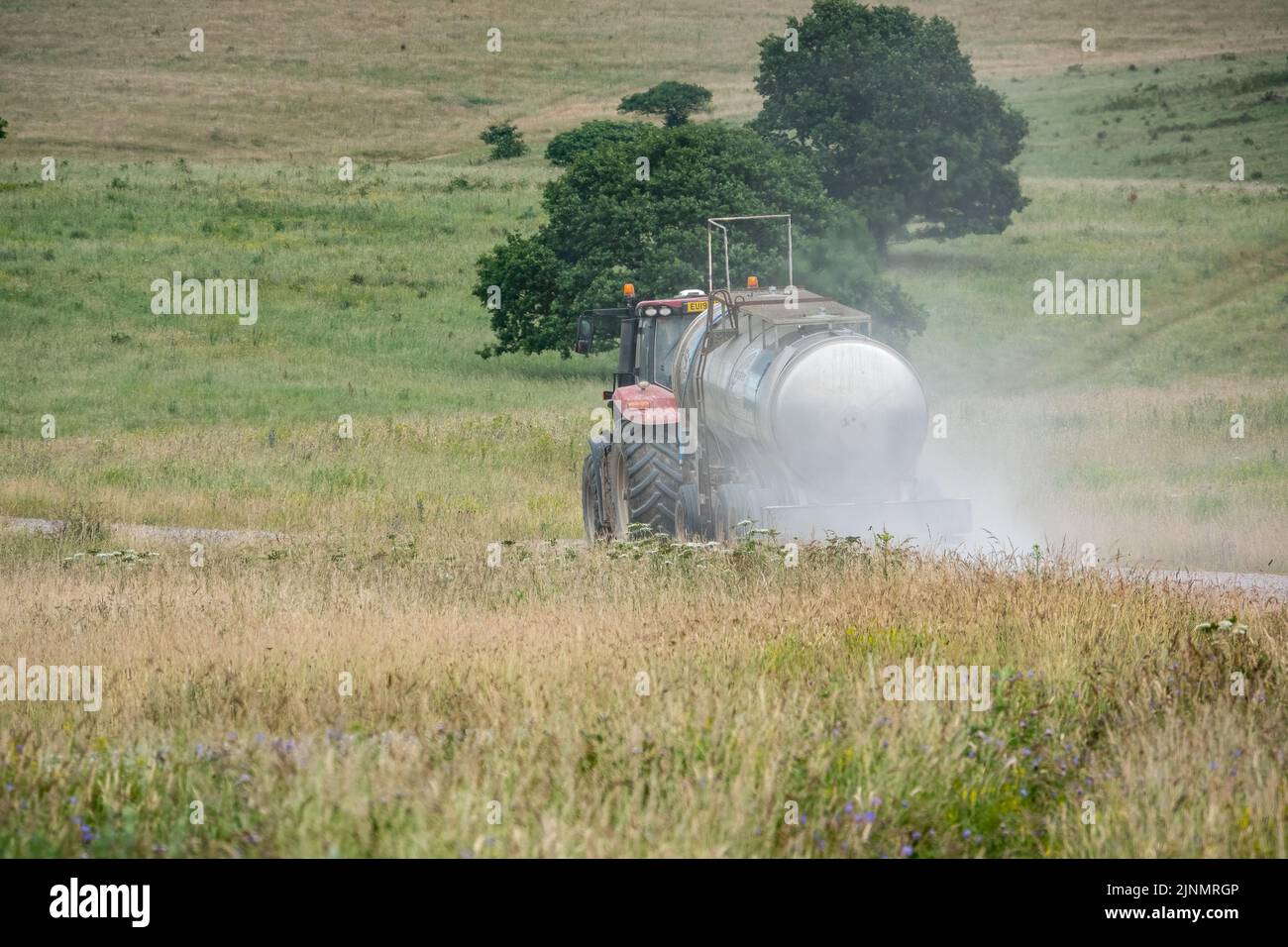 Red Case Puma 340 tractor towing a 30,000 litre water trailer on a dirt ...