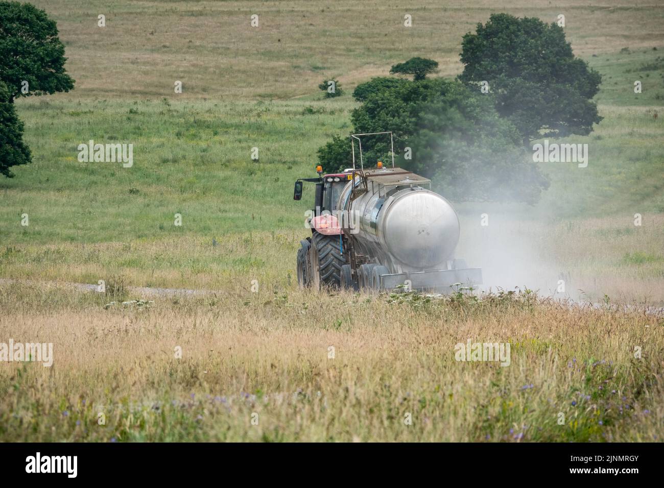 Red Case Puma 340 tractor towing a 30,000 litre water trailer on a dirt ...