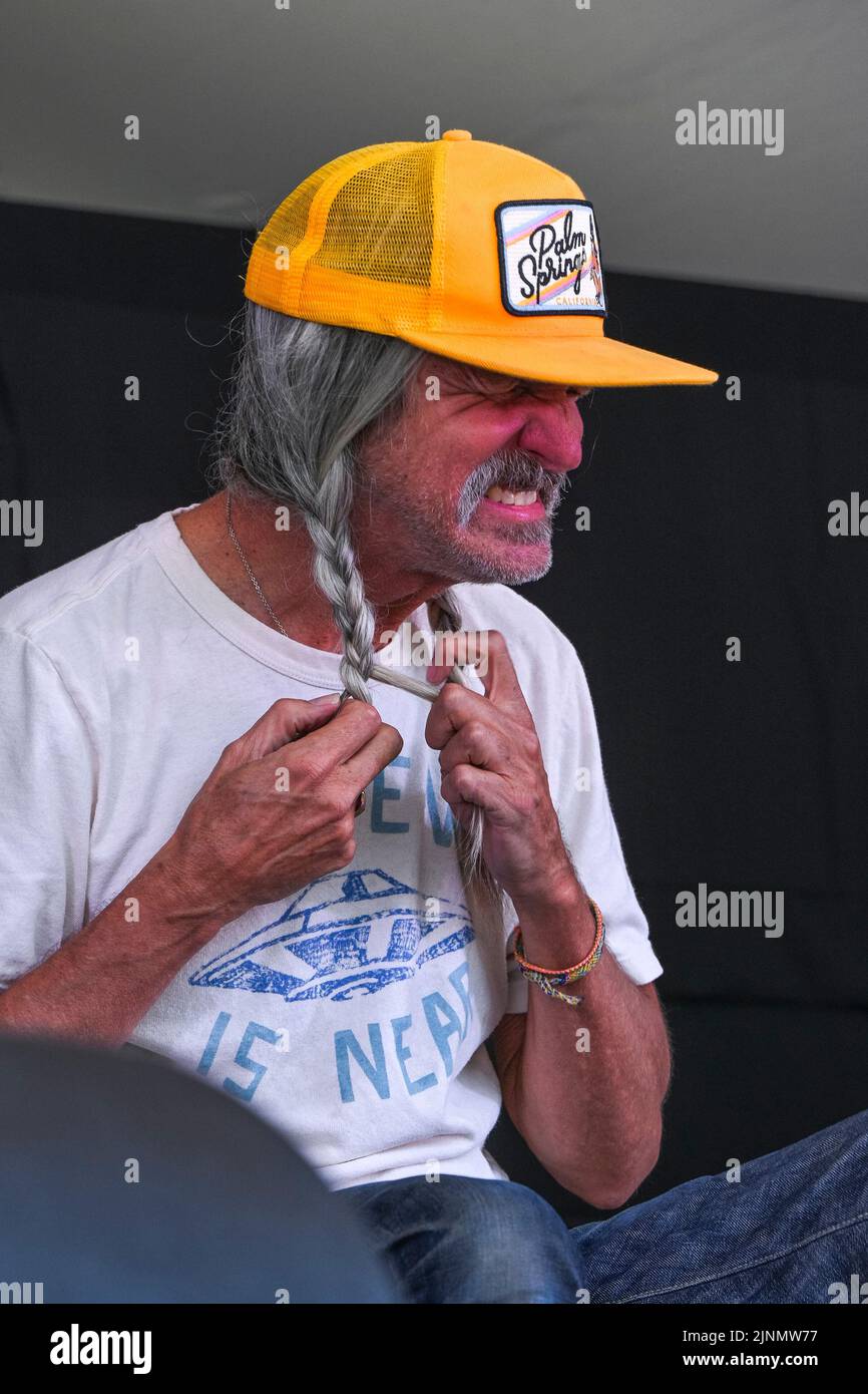 Singer, song writer Steve Poltz braiding his long hair and grimacing ...