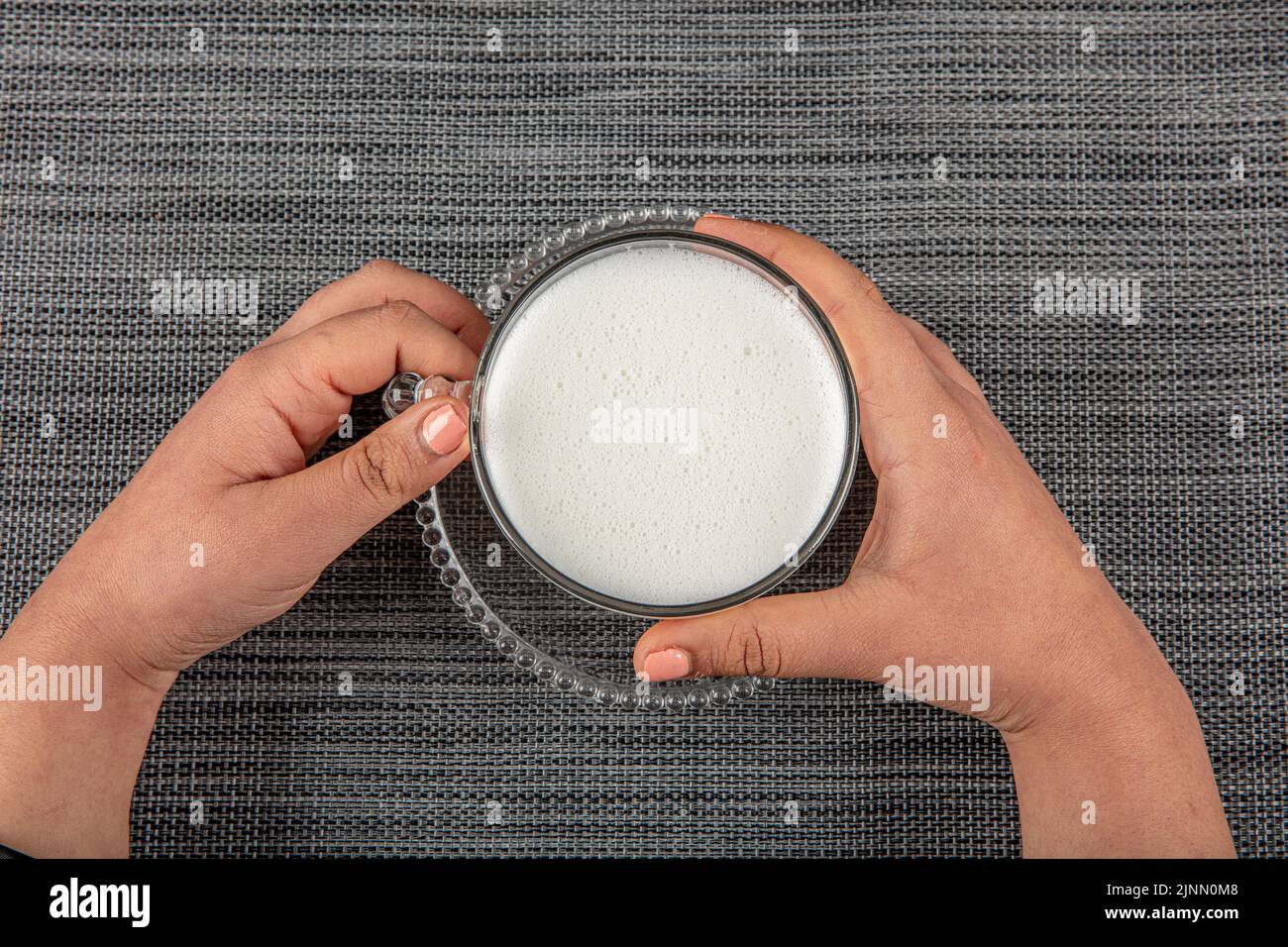 A woman's hand is holding a white cup of hot milk drink with cinnamon ...