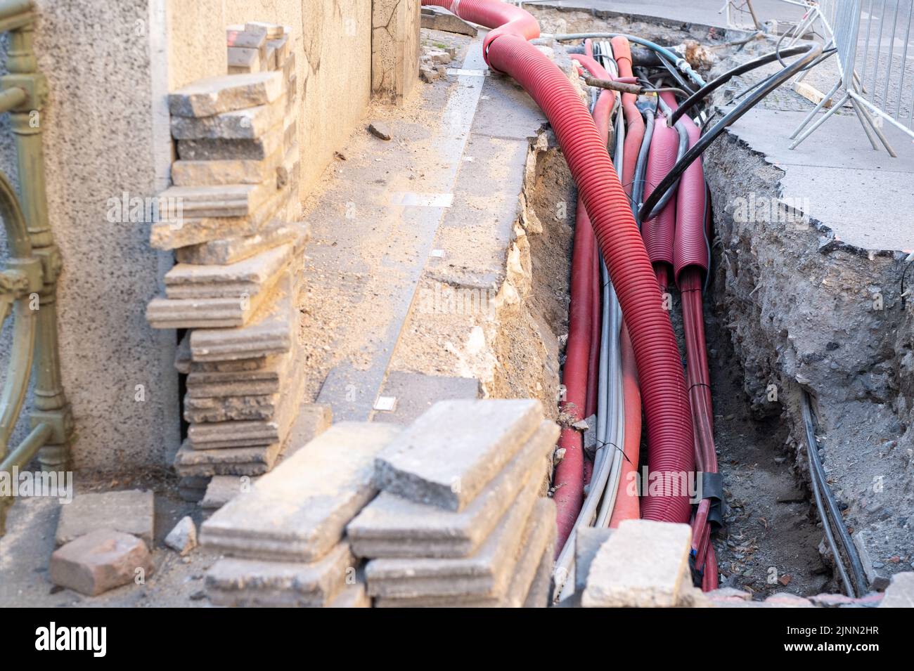 Network cables in red corrugated pipe are buried underground on the ...