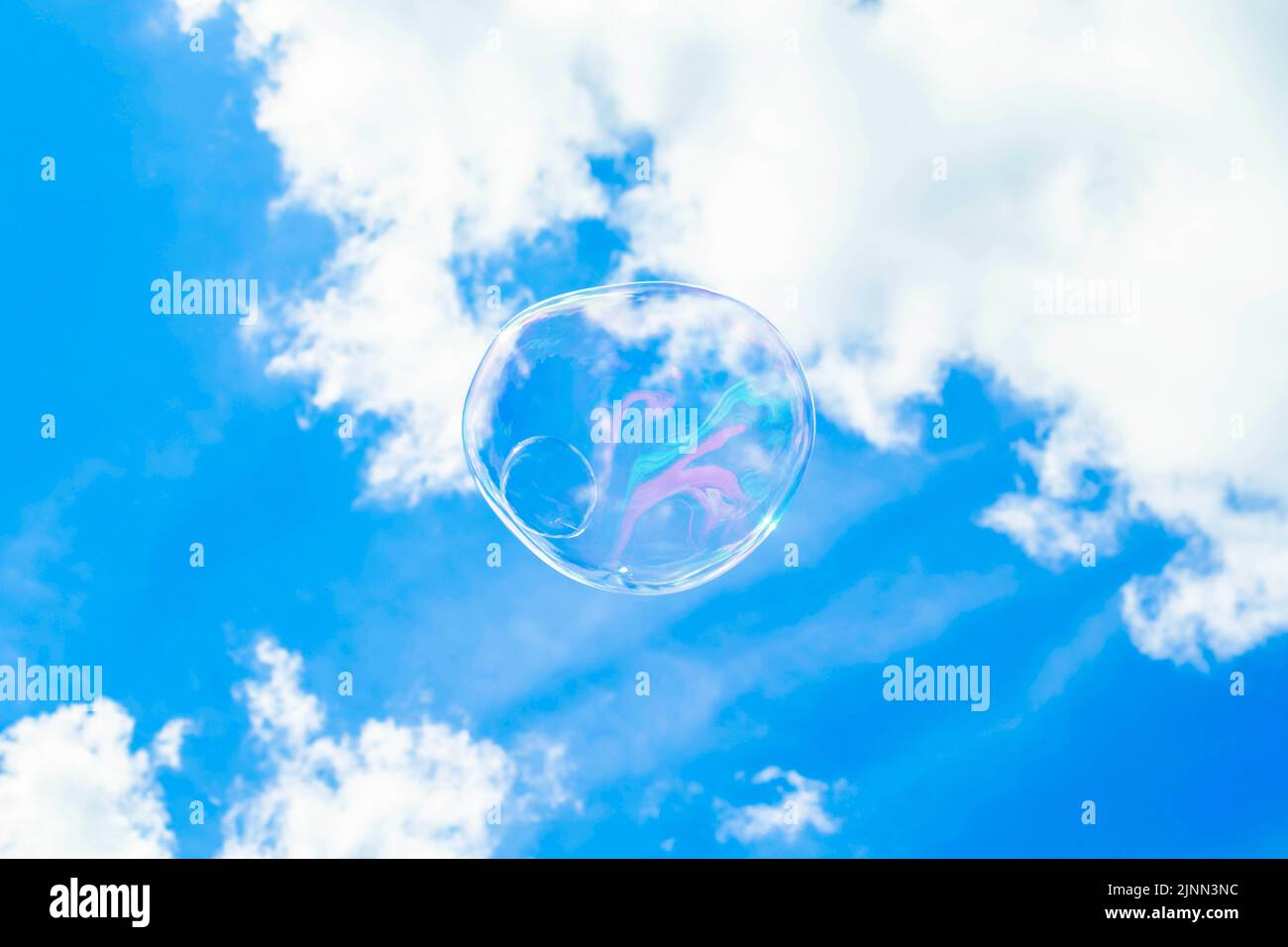 A big bubble floating in the sky, the sky is bright blue behind, the ...