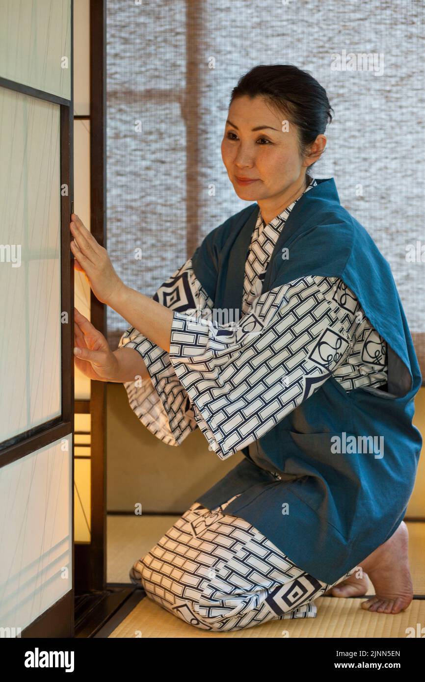 Guest opens shoji screen door at traditional onsen resort in Shizuoka ...