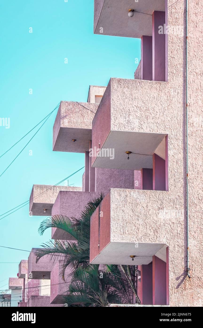 pink building with balconies, palm tree between modules, light cables ...