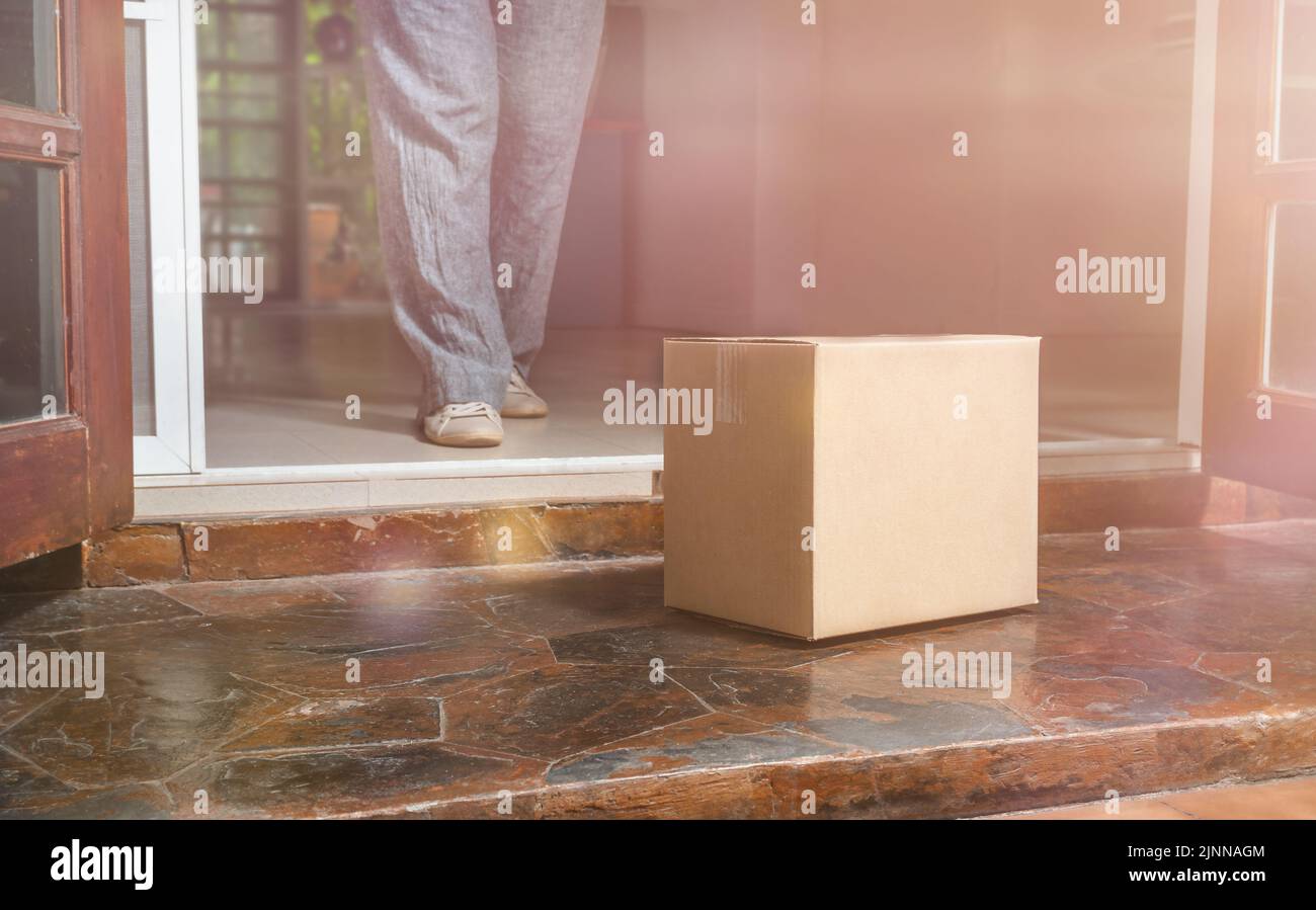 Woman picking up a cardboard box at the doorstep of a delivery Stock ...