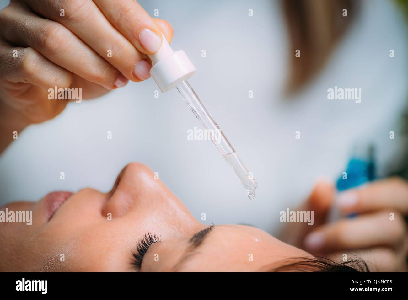 Cosmetician applying serum to woman's face Stock Photo - Alamy
