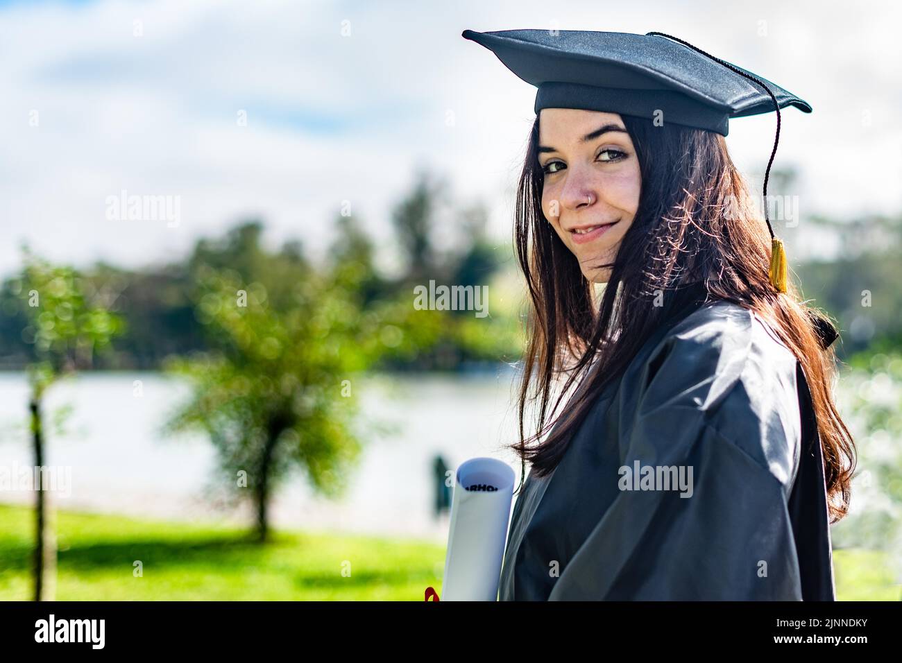 Happy caucasian graduated girl with long brown hair, holding a diploma ...