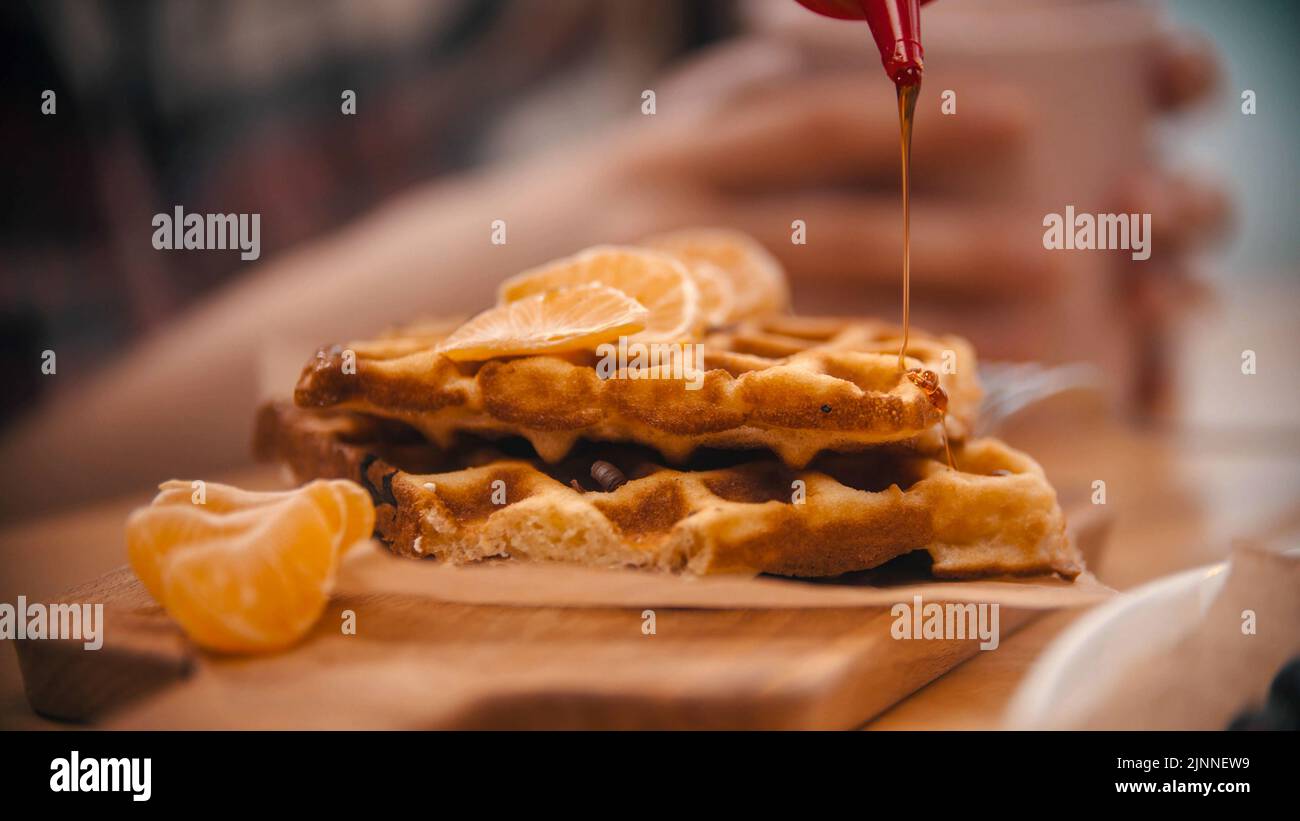 Covering a belgian waffle with a syrup Stock Photo - Alamy