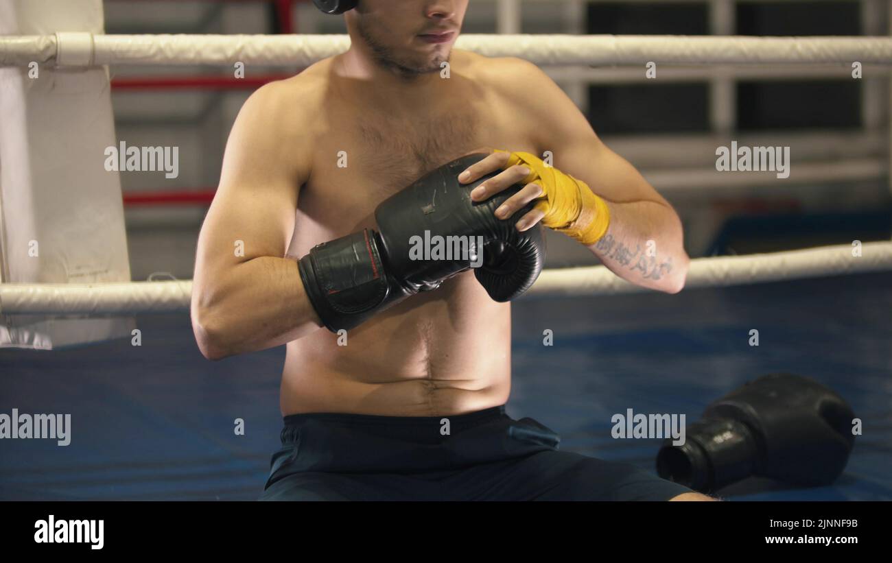 A man boxer sitting on the ring with one boxer glove on Stock Photo - Alamy