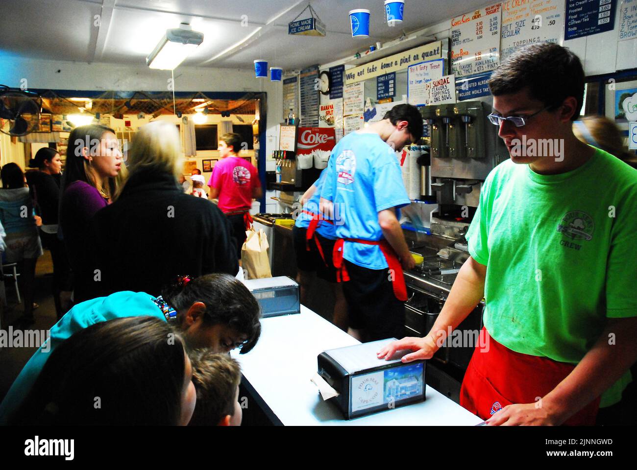 A teenager working at a summer job, takes an order from a family at a ...
