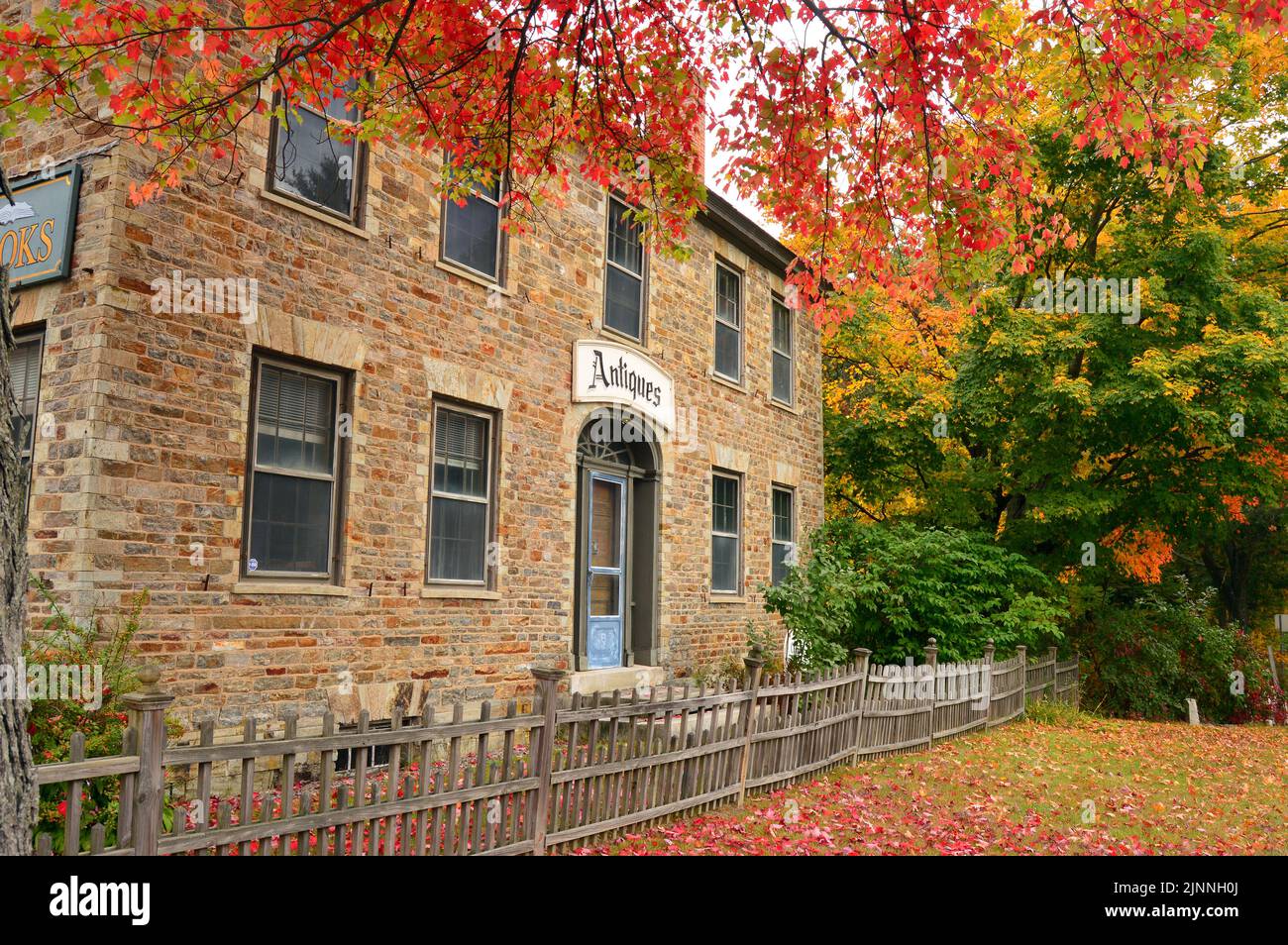 A stone house in autumn is framed by the colorful fall foliage leaves ...