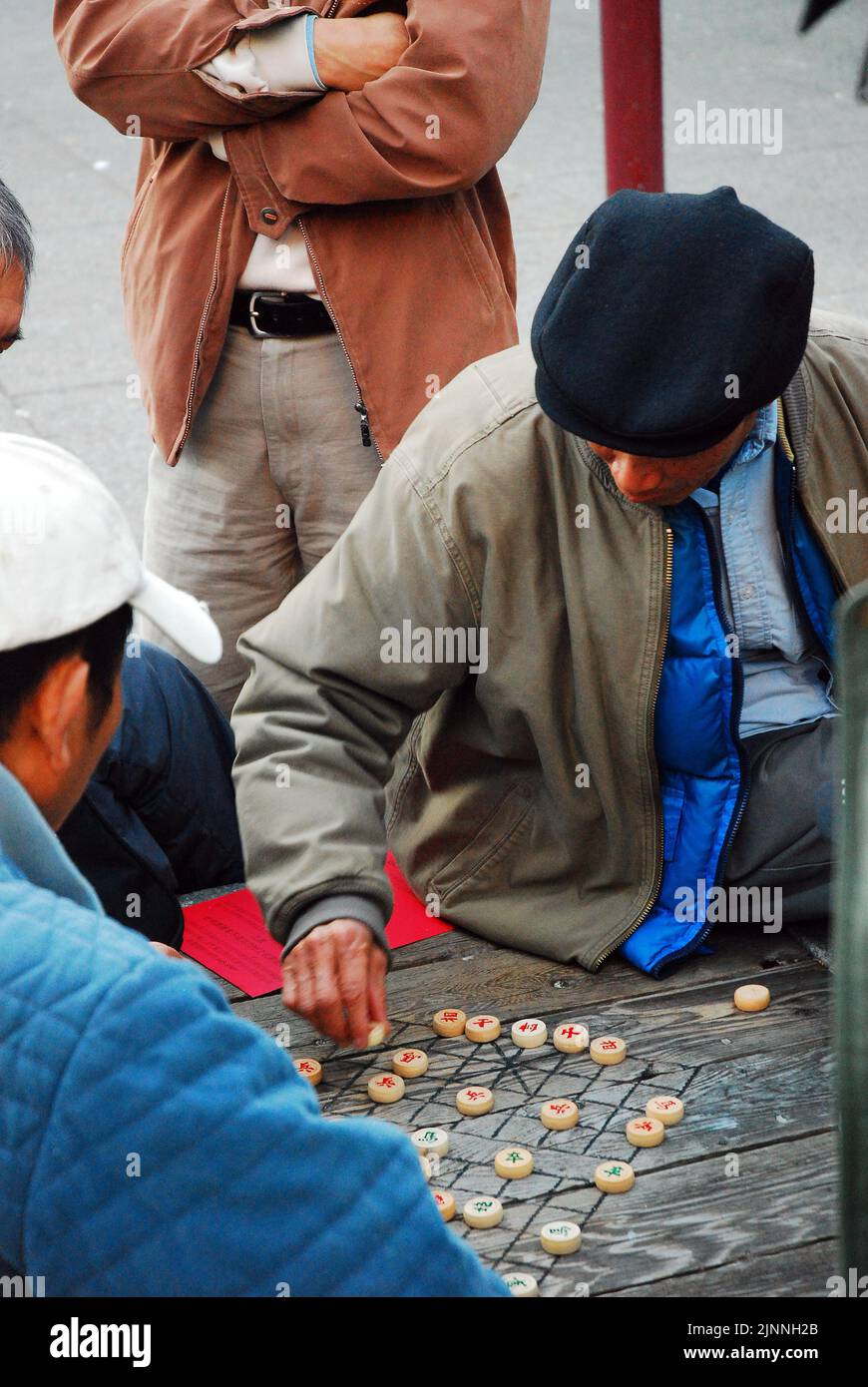 A group of senior Asian friends play xiangqi, a traditional Chinese ...