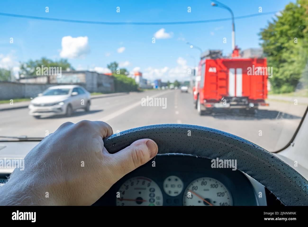driver hand is inside on the steering wheel of a car that is driving ...