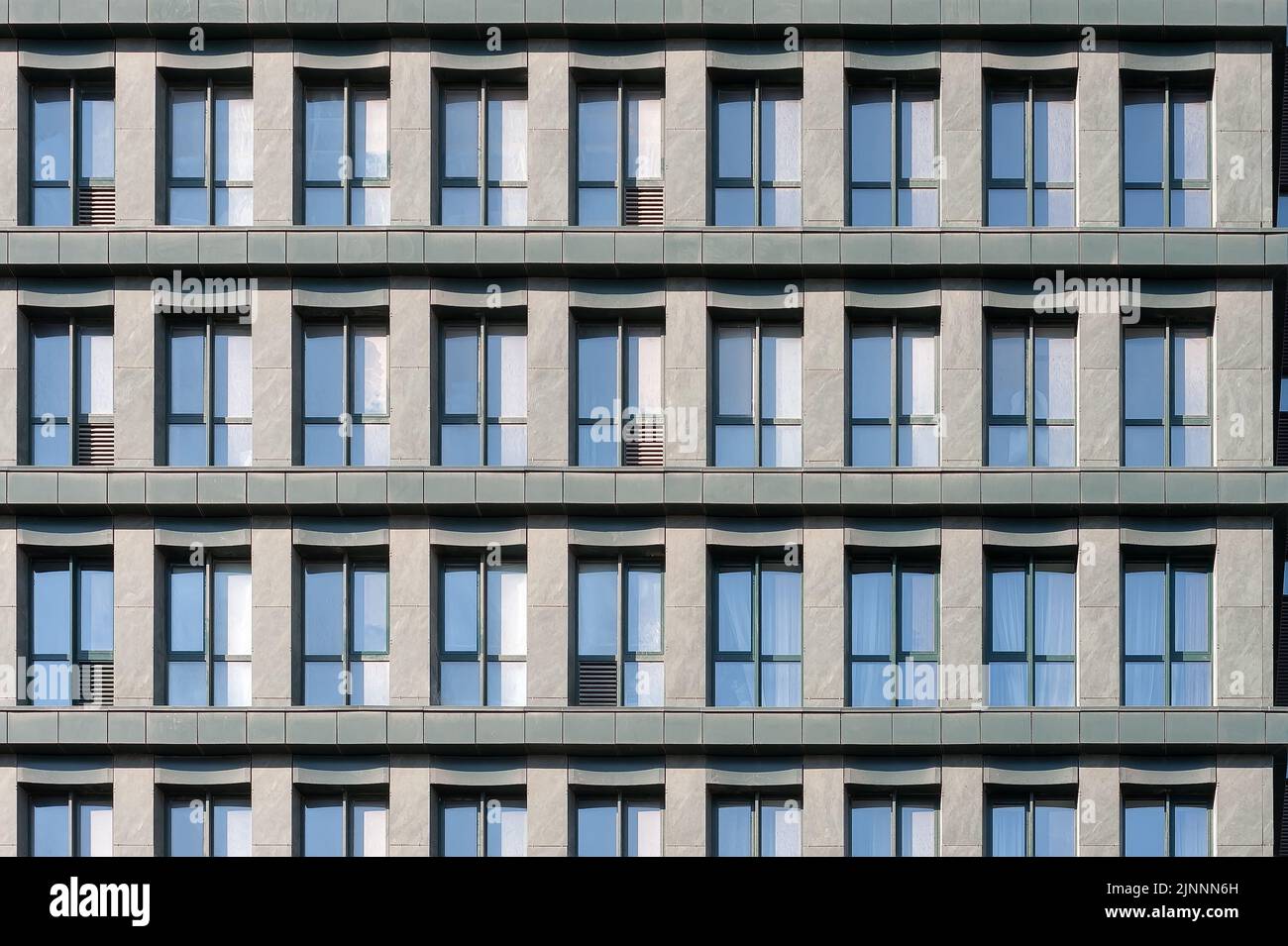 Fragment of common building facade with windows reflecting the sky ...