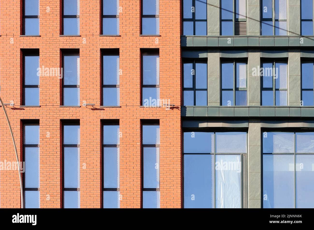 Fragment of common building facade with windows reflecting the sky ...