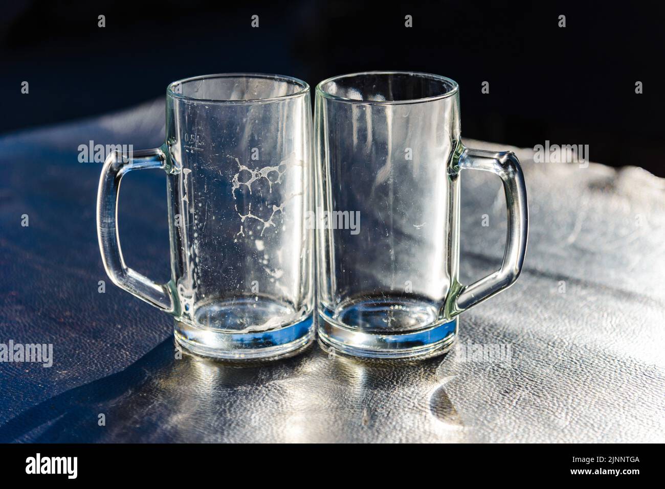 Empty beer two mugs after party on black table at bar table.Two drunk ...