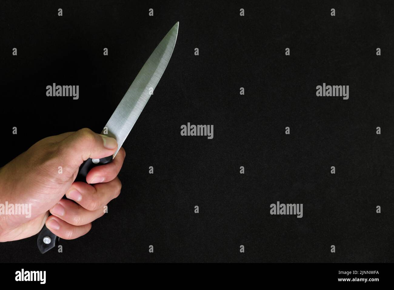Human hand holding a knife in dark black background. Murder, killer and ...