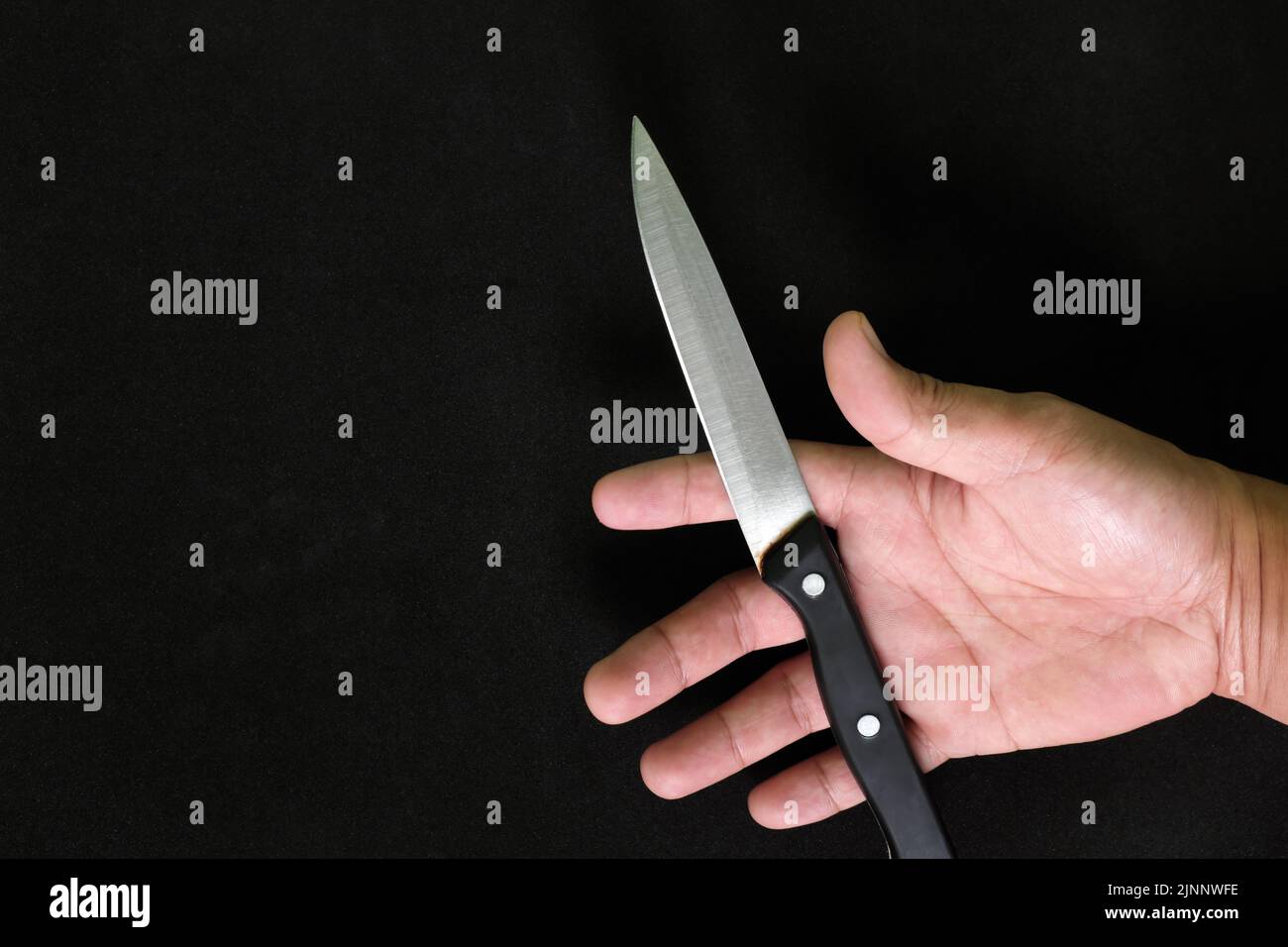 Human hand holding a knife in dark black background. Murder, killer and ...
