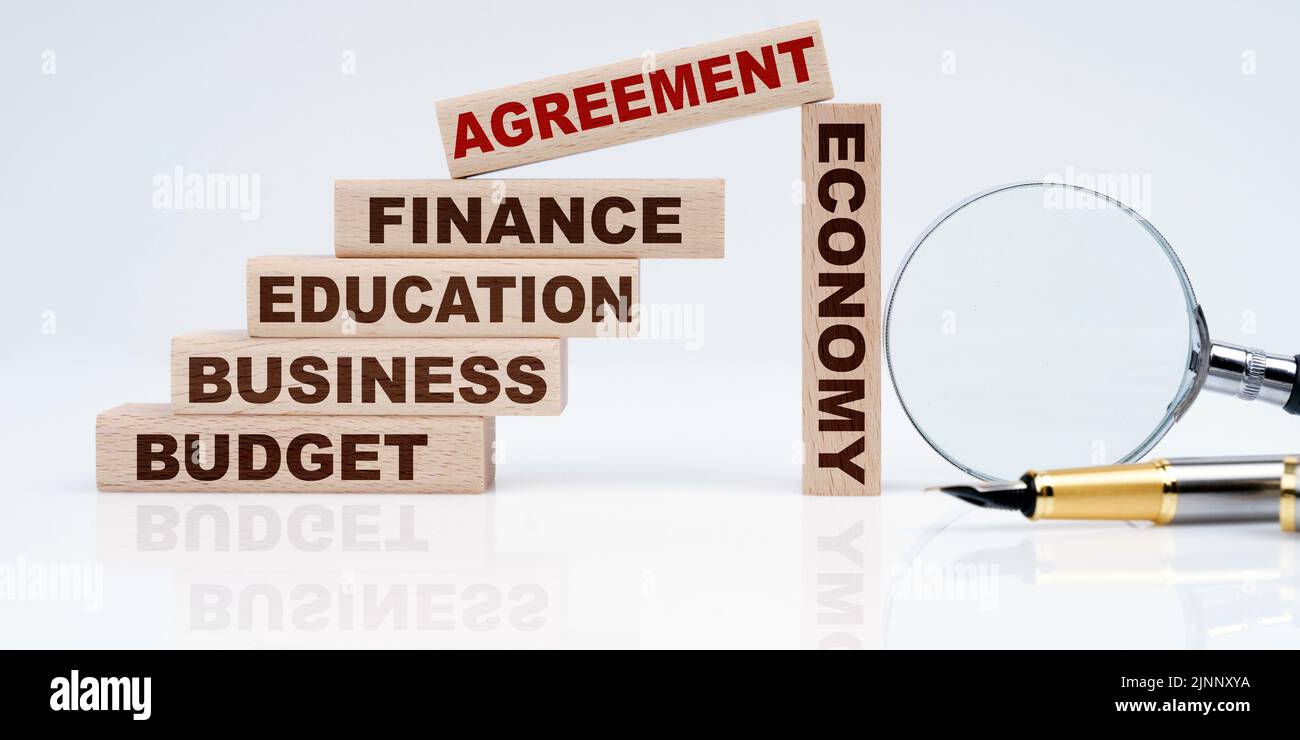 Business and economy concept. Magnifier, pen and wooden blocks with the ...