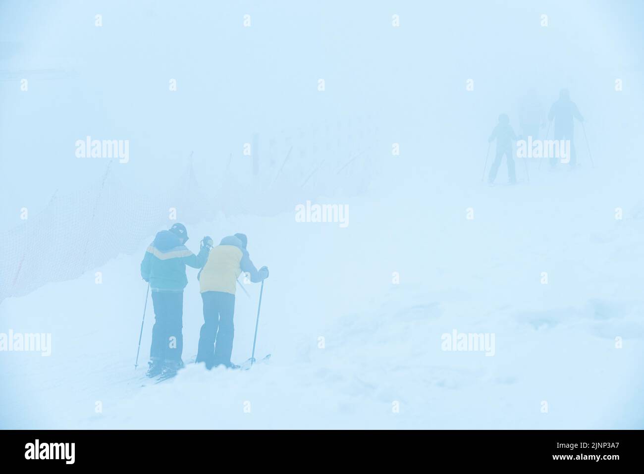 Mountain skiers go on mountain top in heavy snow storm, winter blizzard ...