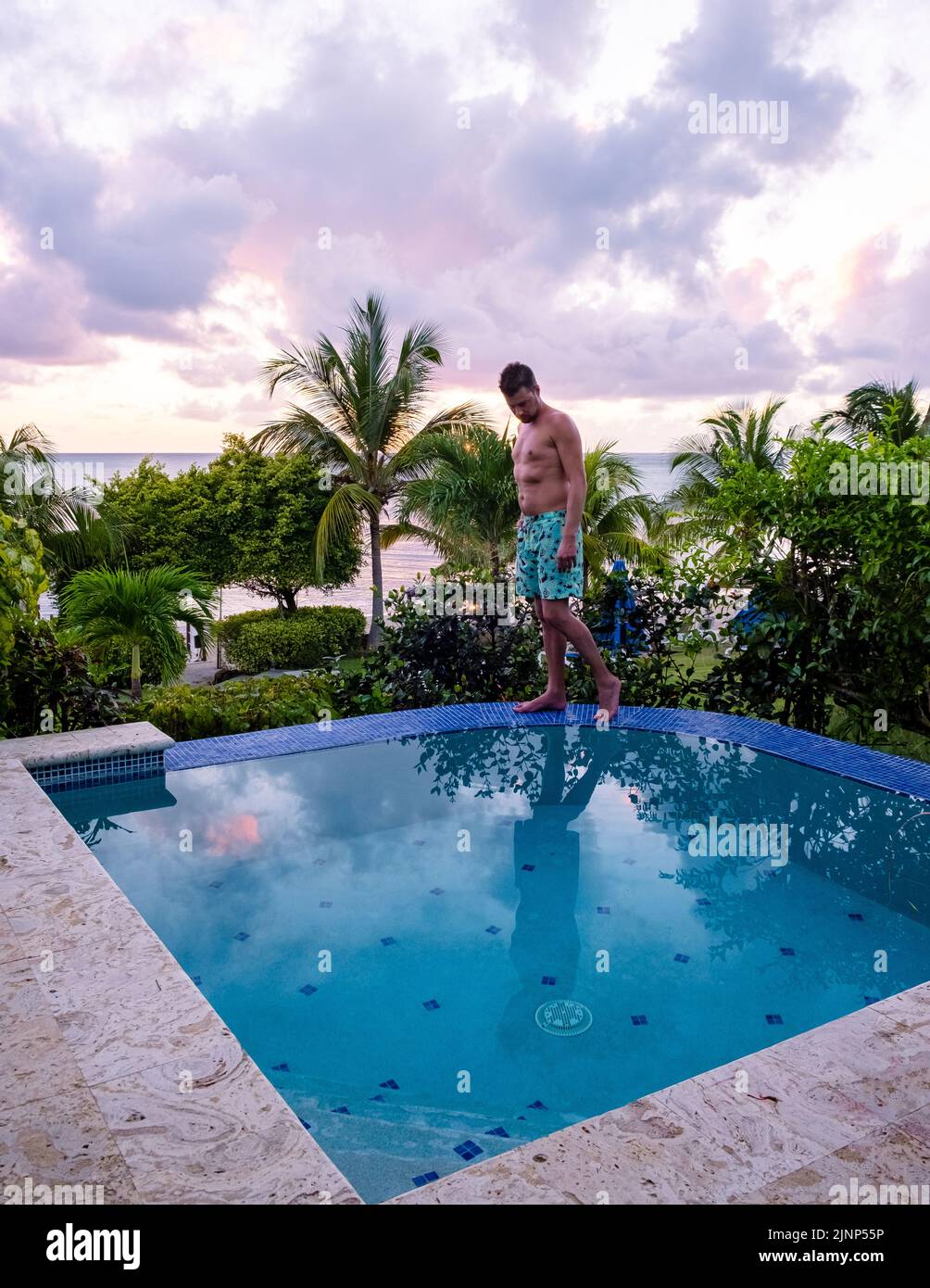 Young men watching the sunset with reflection in the pool at Saint ...