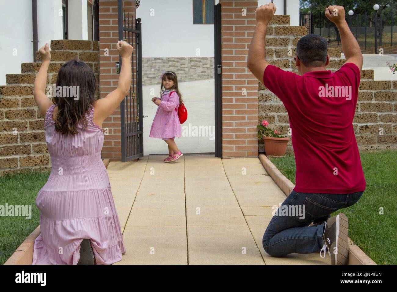 Image of a couple of parents cheering for their daughter with schoolbag ...