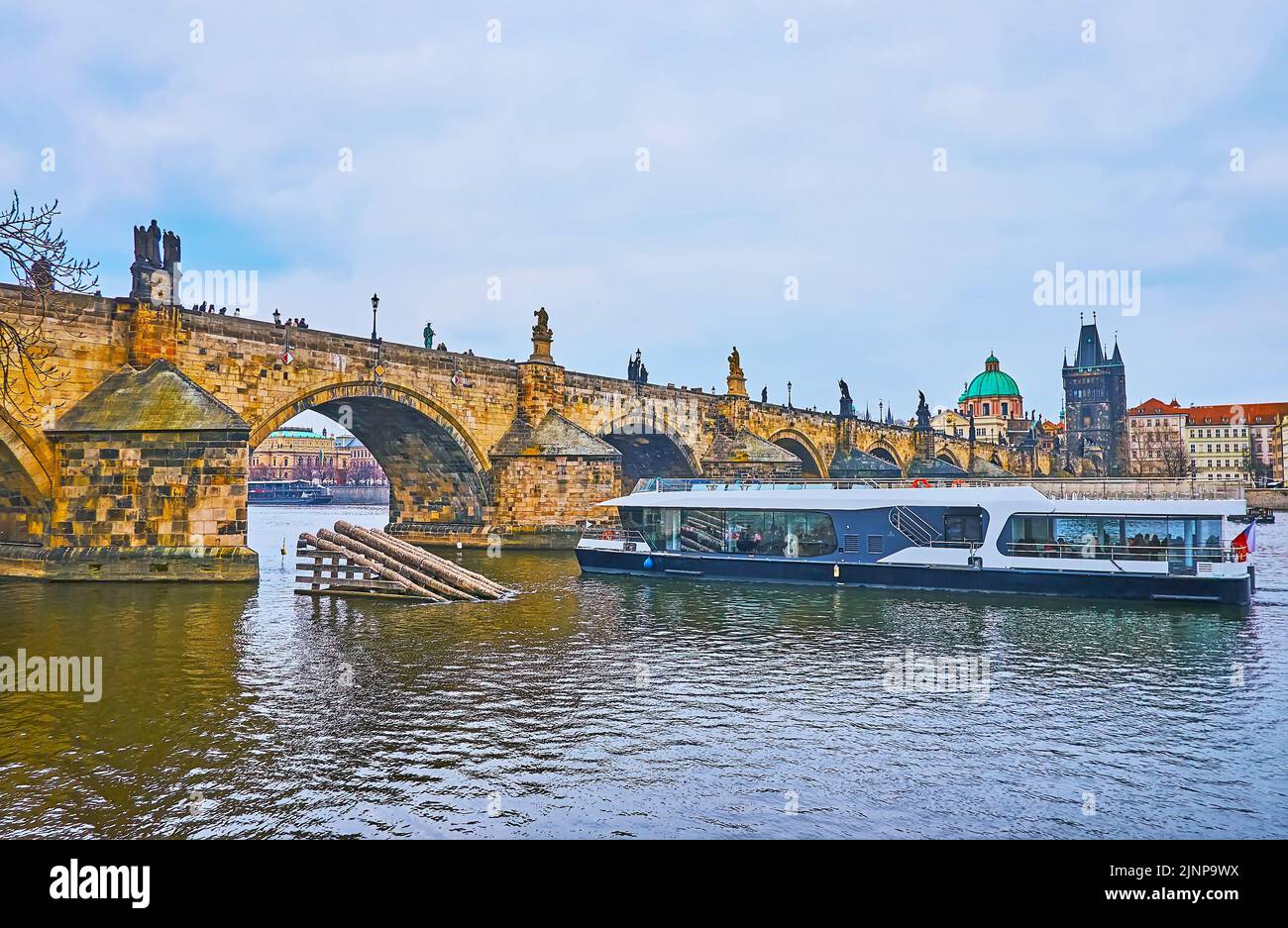 The tourist boat, floating through the arch of Charles Bridge on Vltava ...