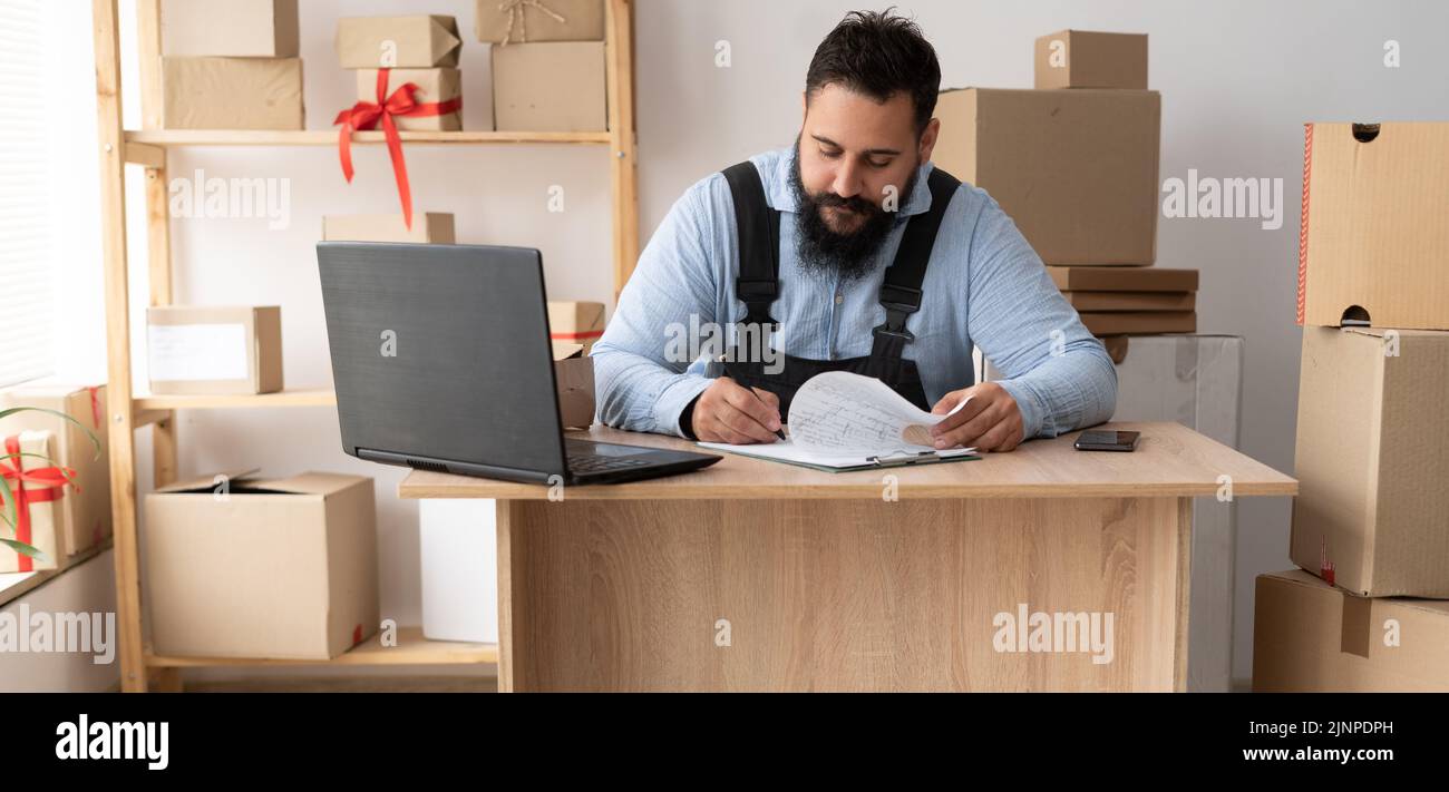 portrait of an indian male business owner, makes a note with a pen on a ...