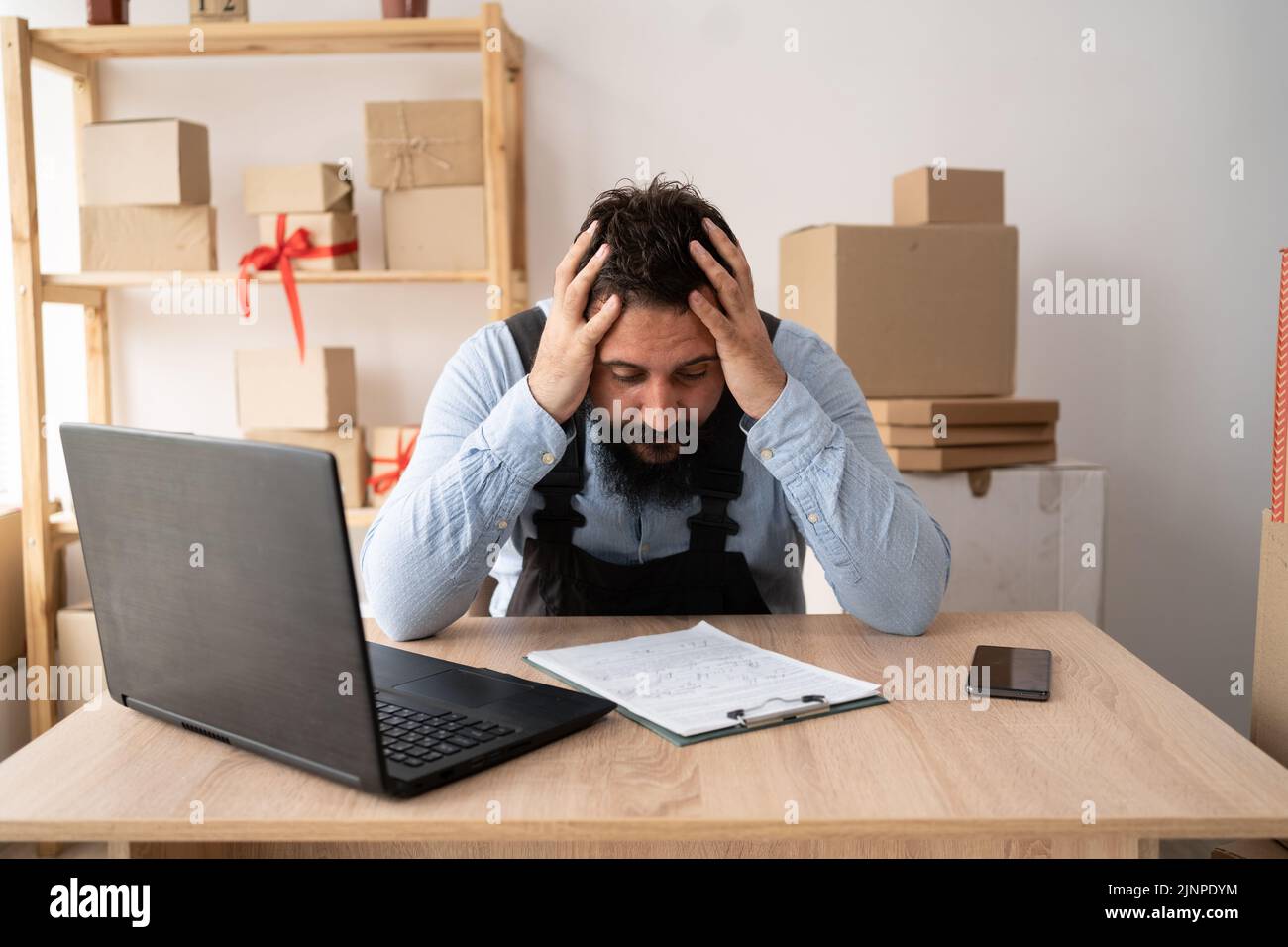 Frustrated business man looking at laptop holding his hands to head in ...