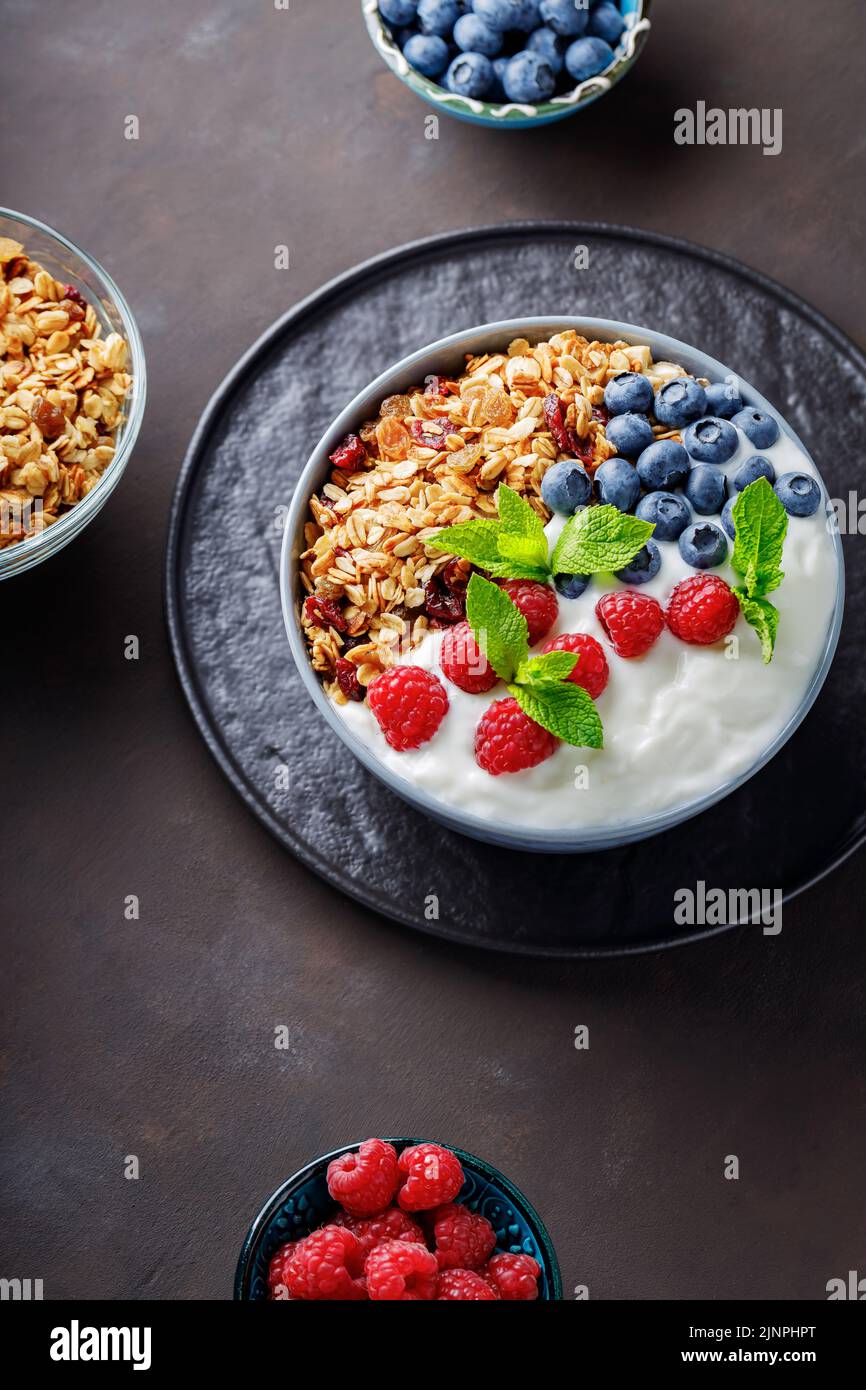 Bowl of granola with yogurt and fresh berries on a dark background ...