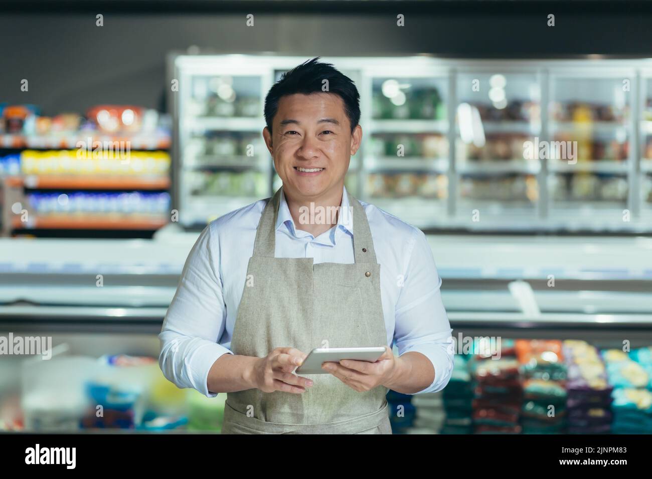 portrait of handsome asian staff man salesman in apron standing and ...